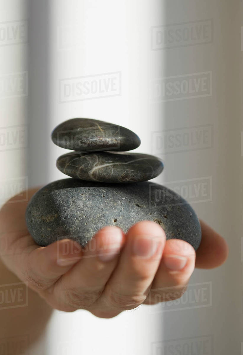 Close up of hand holding three stones - Stock Photo - Dissolve