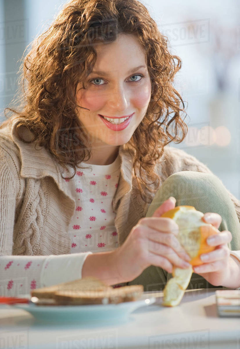Portrait of woman peeling orange - Royalty-free Stock Photo | Dissolve