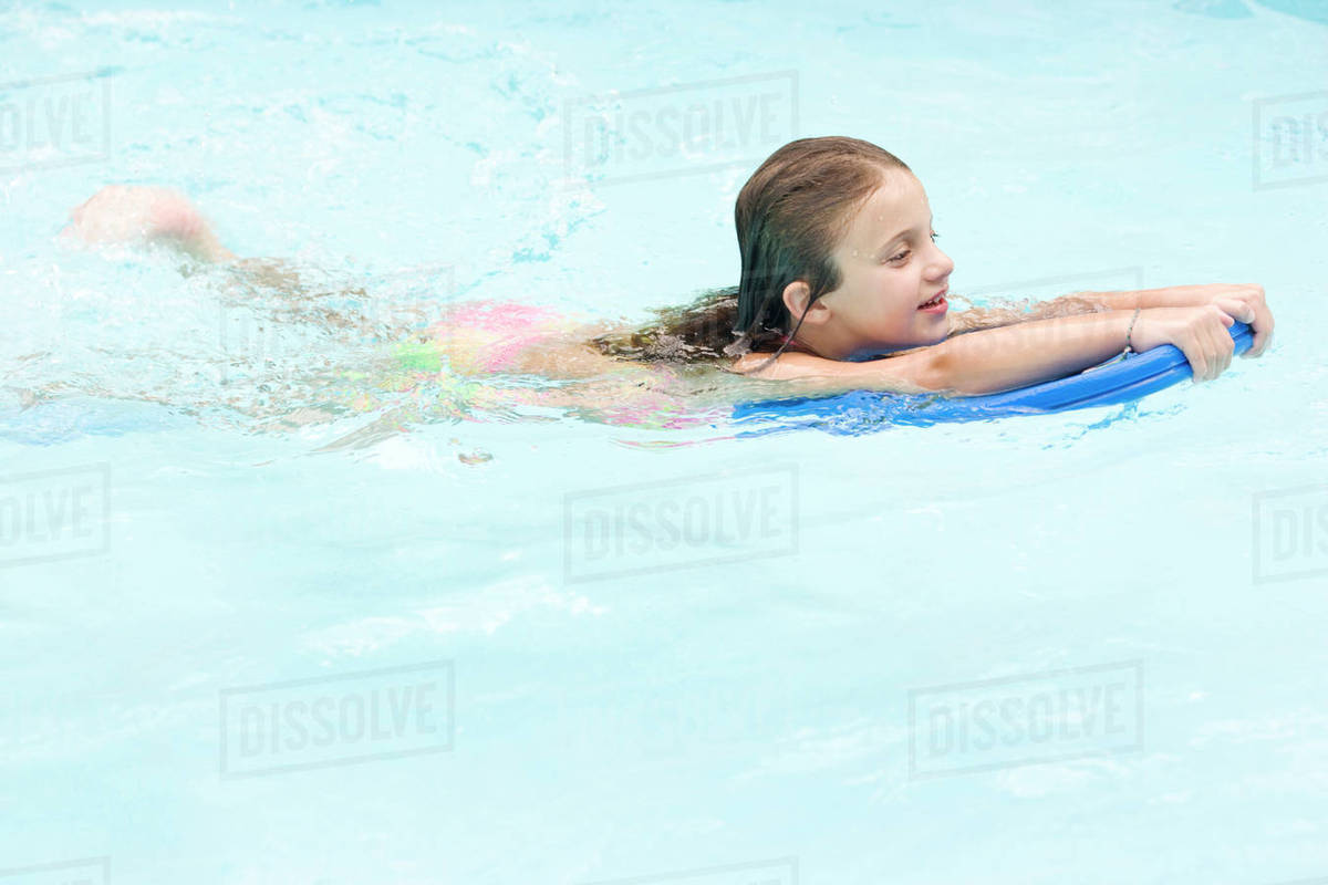 Girl using kickboard in swimming pool - Stock Photo - Dissolve