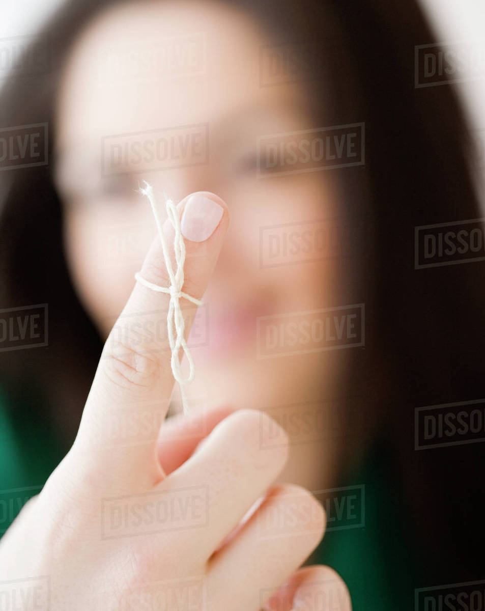 Woman with string tied around finger - Stock Photo - Dissolve