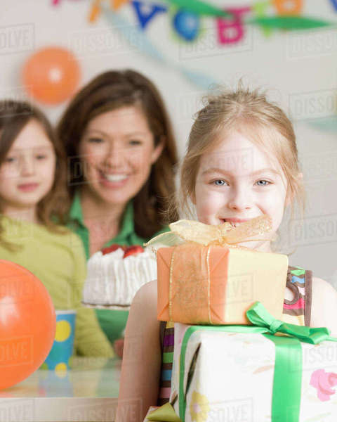 Girl holding stack of birthday gifts - Stock Photo - Dissolve