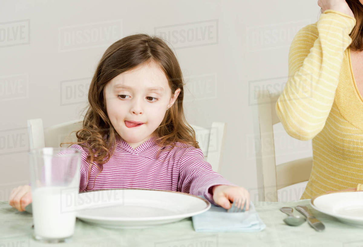 Girl sitting at dinner table - Stock Photo - Dissolve