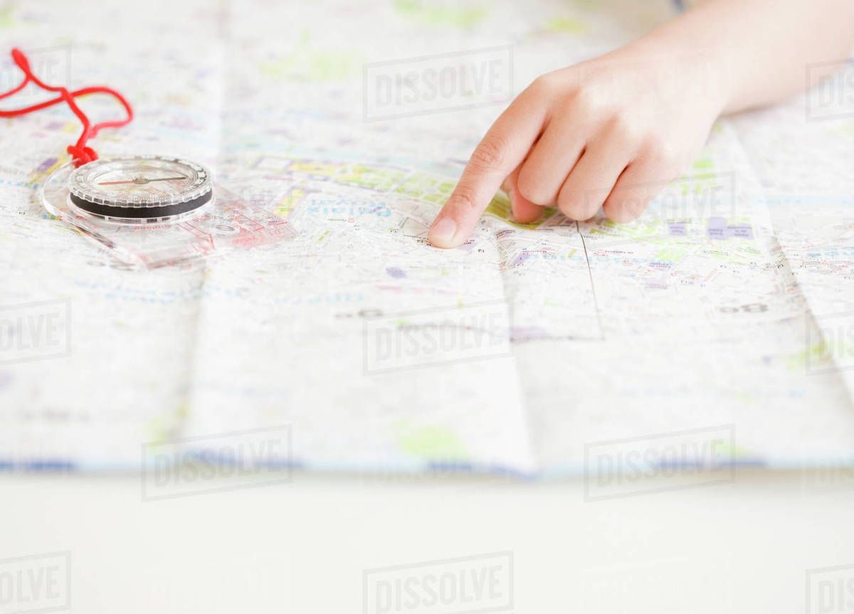 Child pointing at map next to compass - Royalty-free Stock Photo | Dissolve