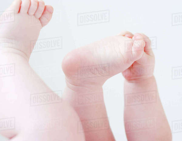 Close up of baby grabbing feet - Royalty-free Stock Photo | Dissolve
