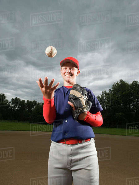 Baseball pitcher tossing ball in air - Stock Photo - Dissolve