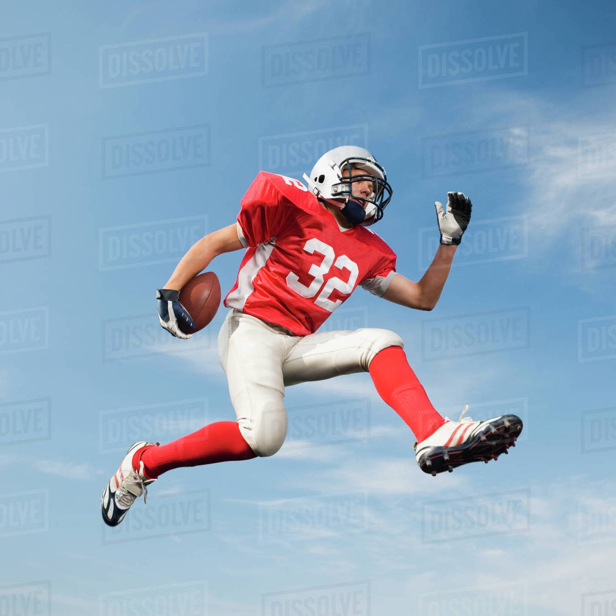 Football player in mid-air holding football - Royalty-free Stock Photo ...