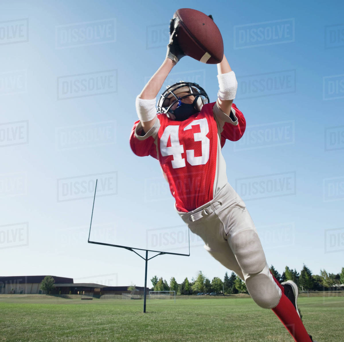 Football player in mid-air reaching for football - Royalty-free Stock ...