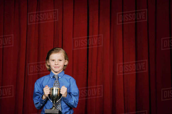 Boy holding trophy on stage - Royalty-free Stock Photo | Dissolve