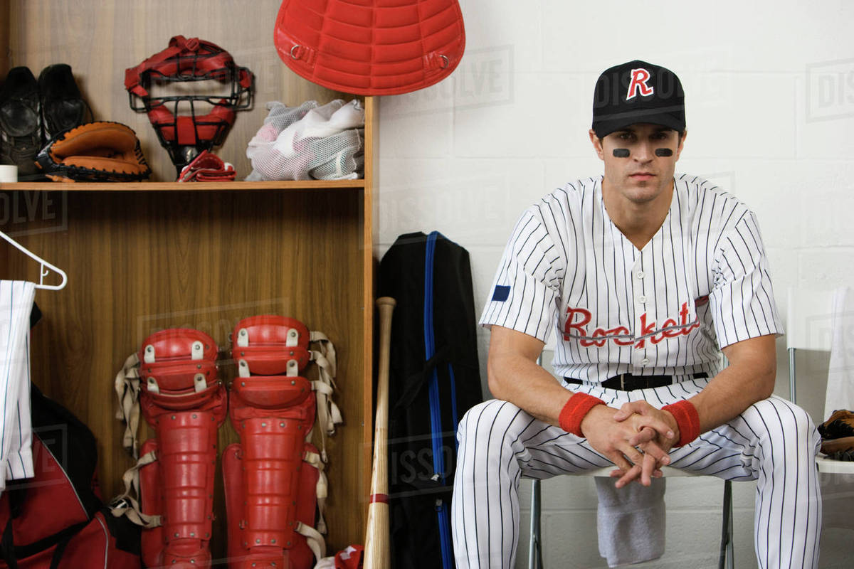 Portrait of baseball player sitting in locker room - Stock Photo - Dissolve