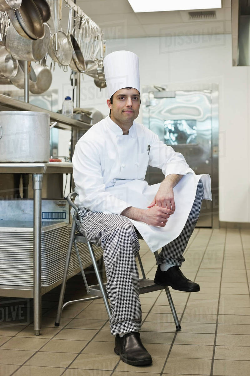 Chef sitting on stool in kitchen - Royalty-free Stock Photo | Dissolve
