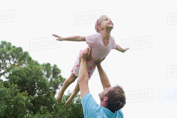 Father lifting daughter in backyard - Royalty-free Stock Photo | Dissolve