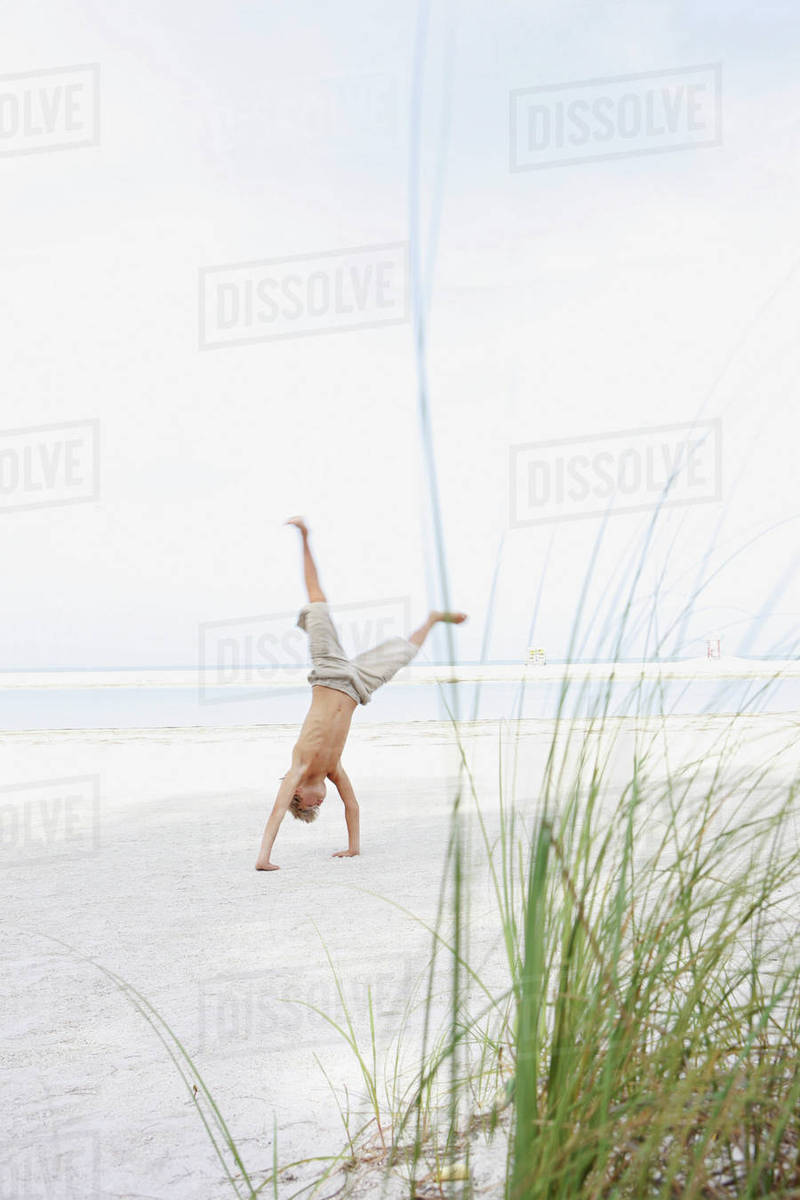 Boy doing cartwheel on beach - Royalty-free Stock Photo | Dissolve