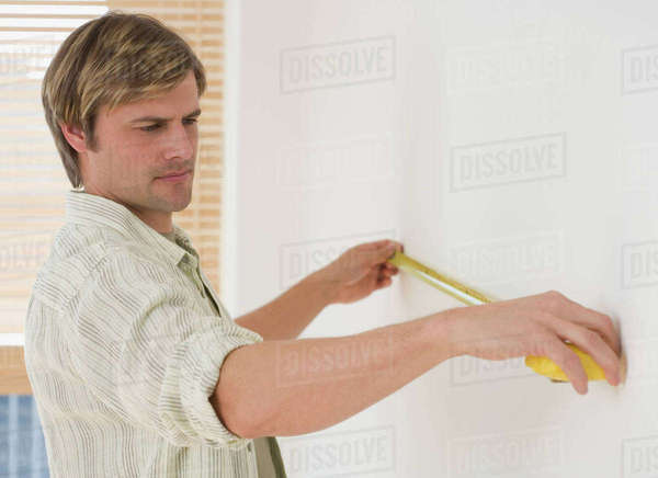 Man measuring wall with tape measure - Royalty-free Stock Photo | Dissolve