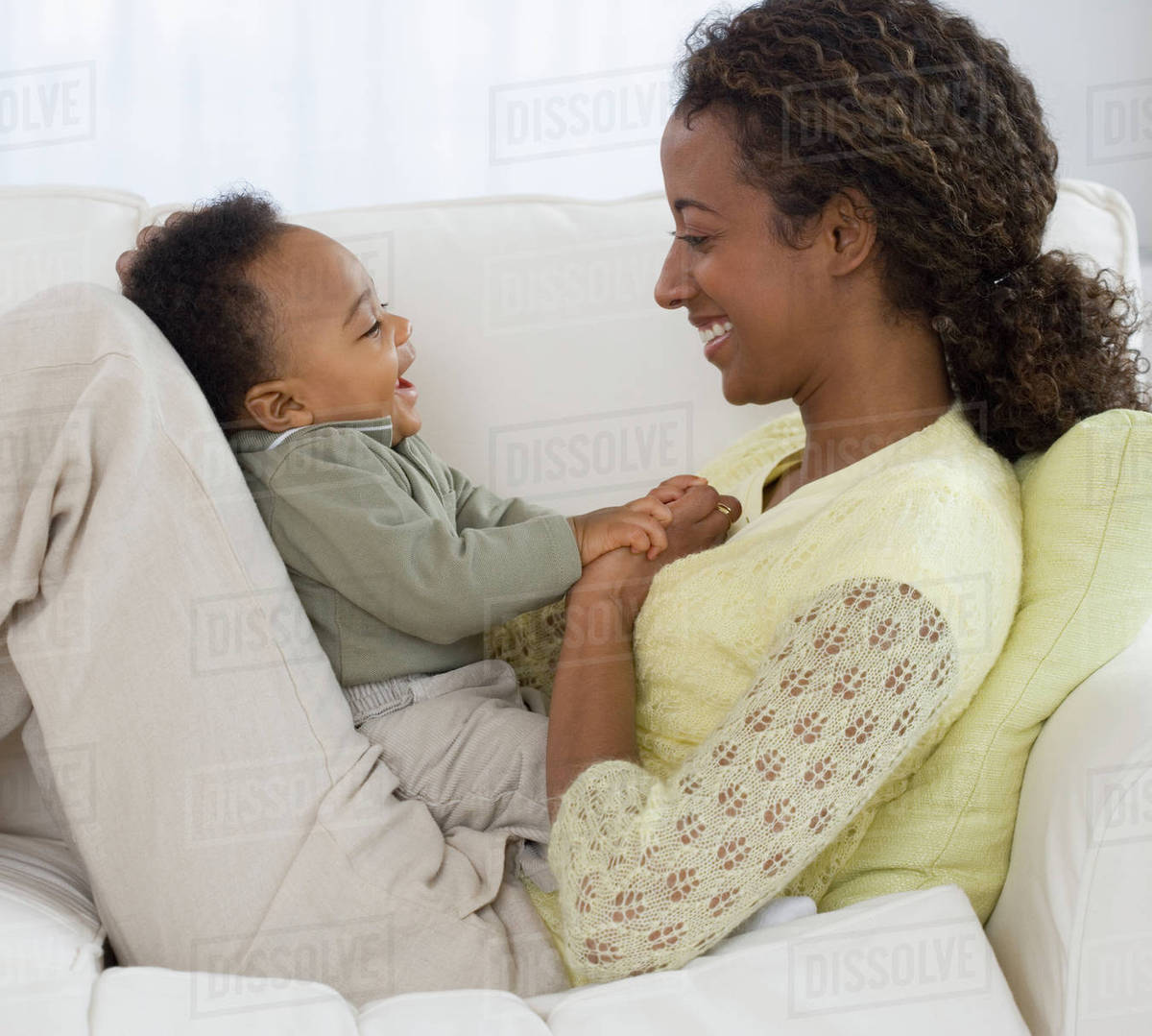 Mother and baby laughing on sofa - Stock Photo - Dissolve