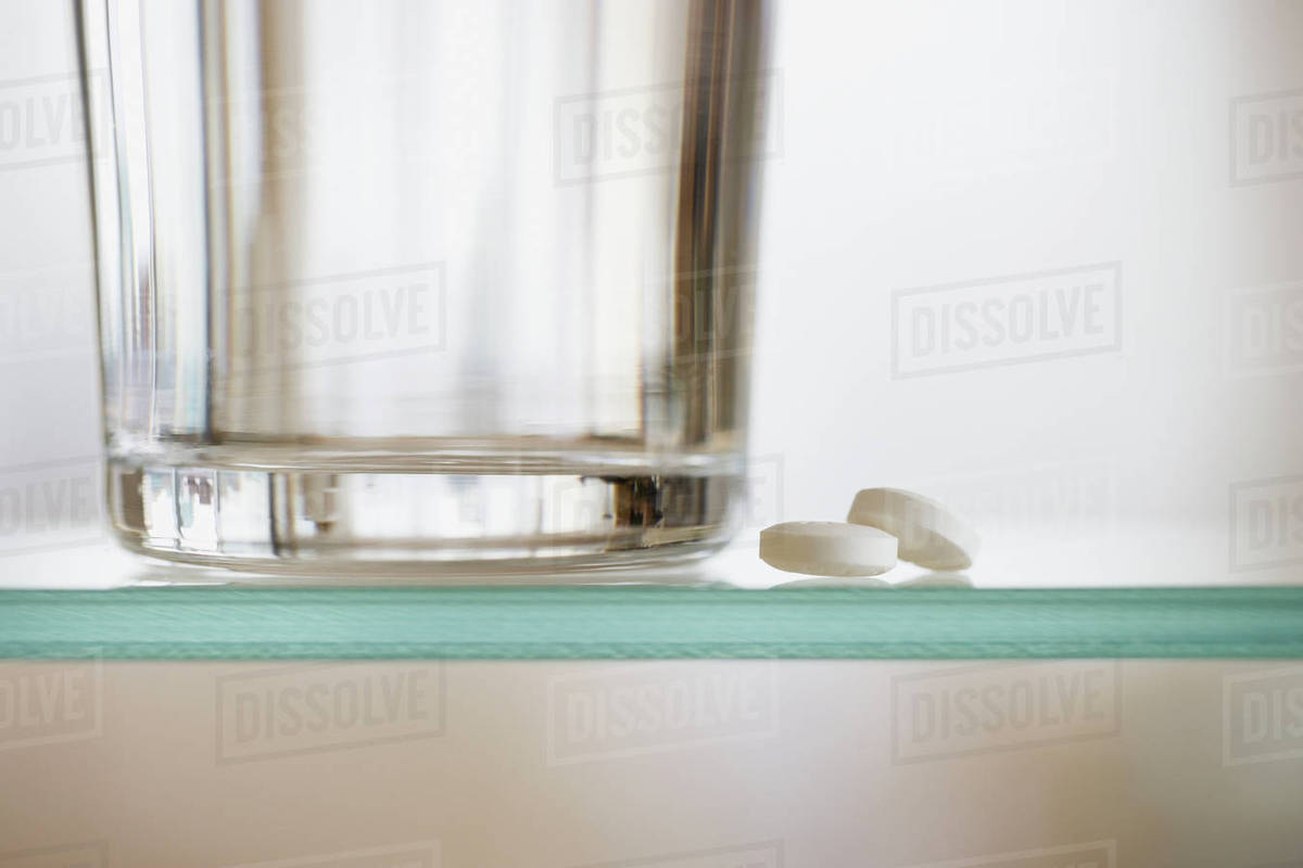 Medication and water glass on shelf - Royalty-free Stock Photo | Dissolve