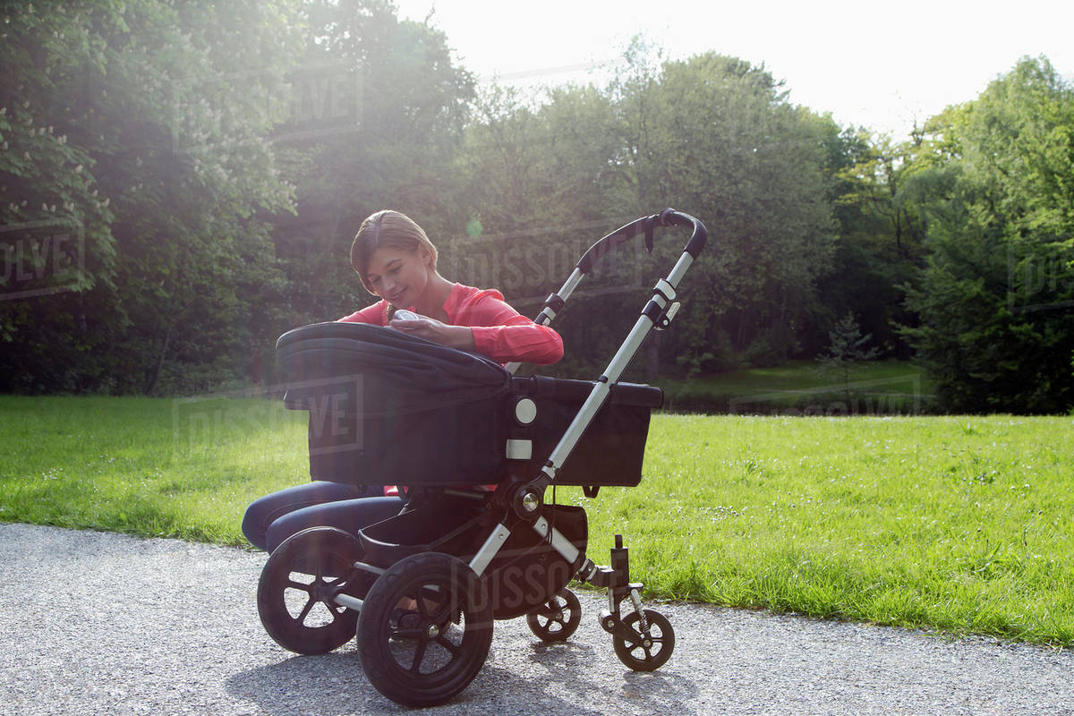 Mother with pram in park - Stock Photo - Dissolve