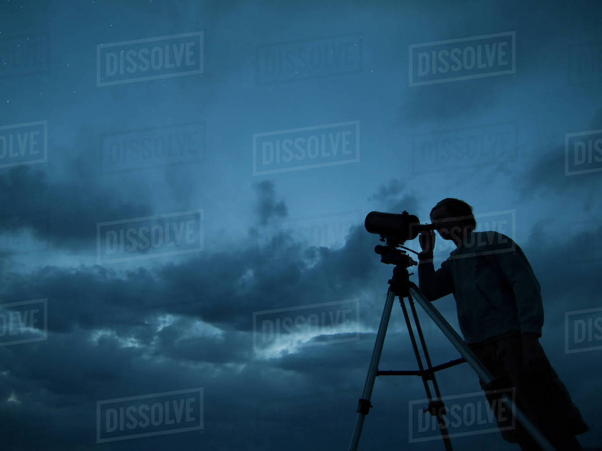 Man using telescope on tripod - Royalty-free Stock Photo | Dissolve