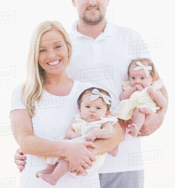 Studio shot portrait of happy family with two baby girls (2-5 months ...