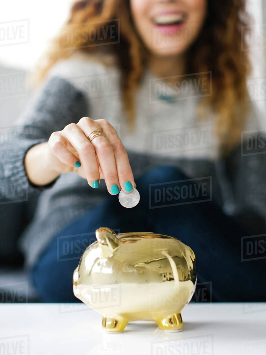 Woman dropping coin into gold piggy bank - Royalty-free Stock Photo ...