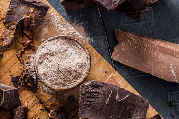 Various chocolate pieces and chocolate powder on cutting board - Stock ...