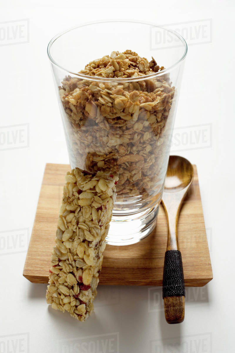 Crunchy muesli in a glass, muesli bar in front - Stock Photo - Dissolve