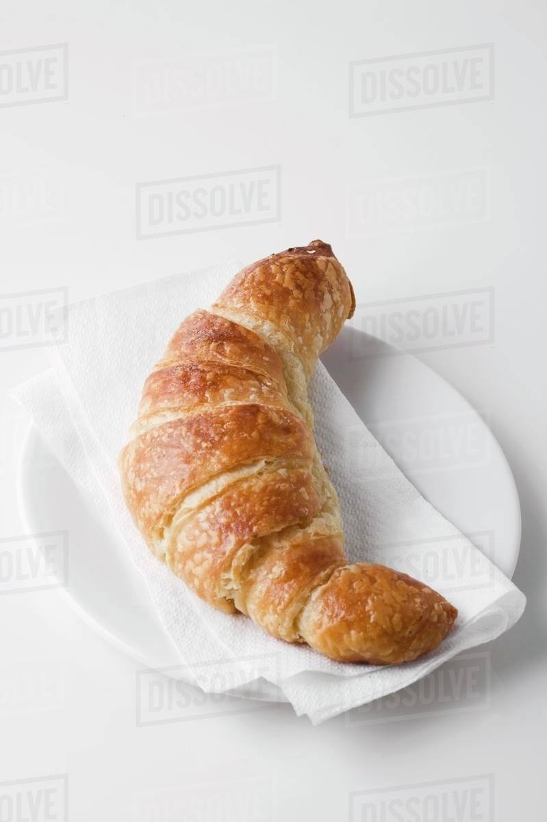 Croissant with paper napkin on plate - Stock Photo - Dissolve
