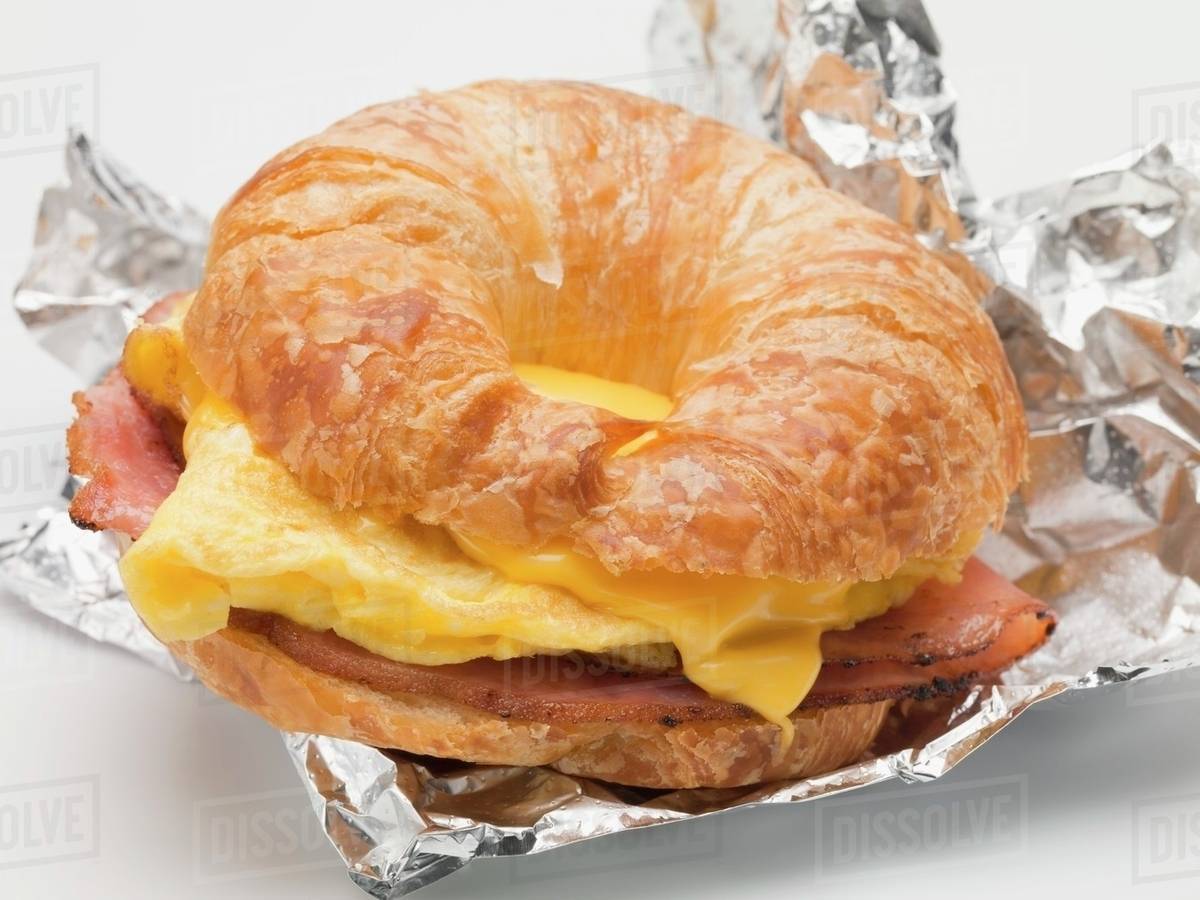 Croissant filled with scrambled egg, cheese & bacon on foil - Royalty ...