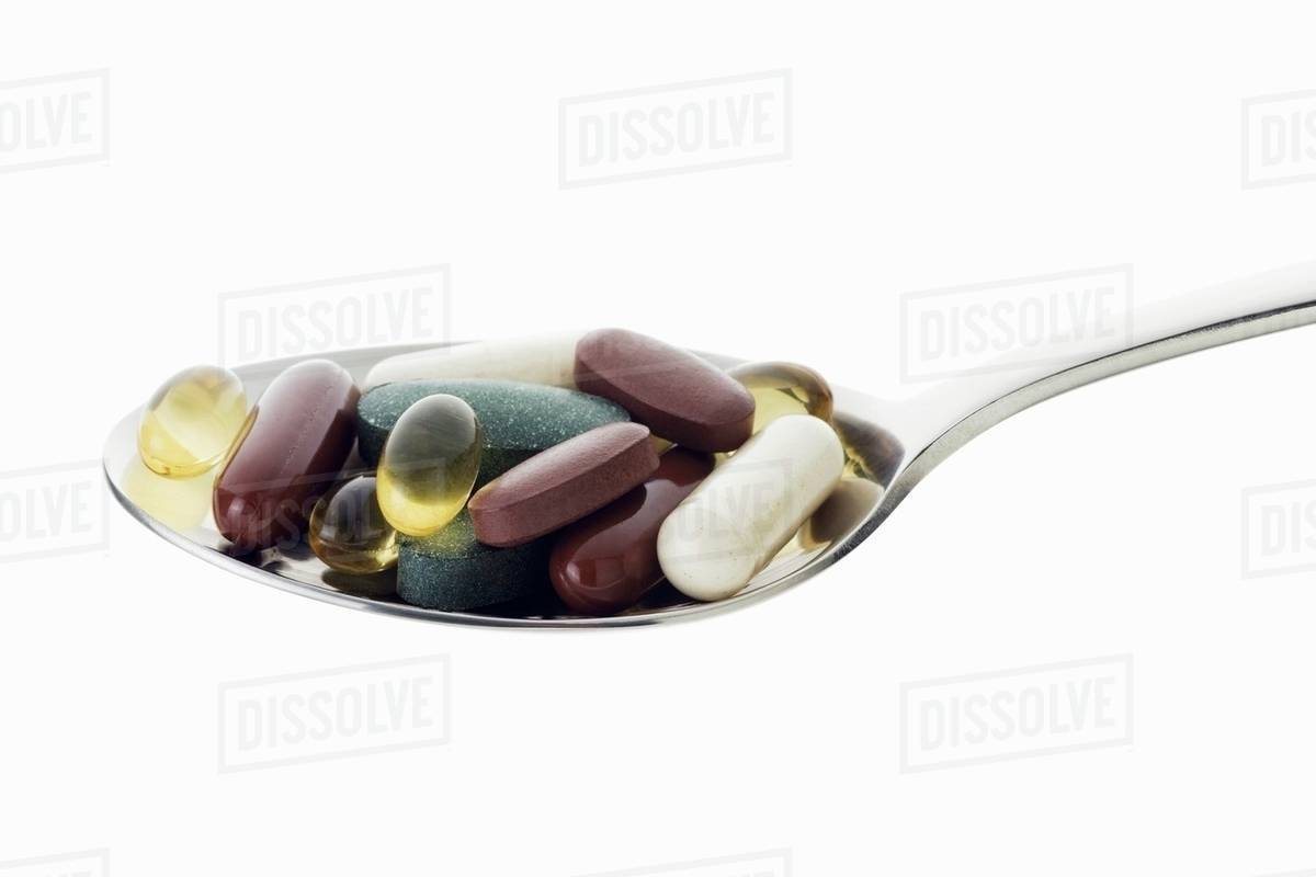 Assorted tablets and capsules on spoon - Stock Photo - Dissolve