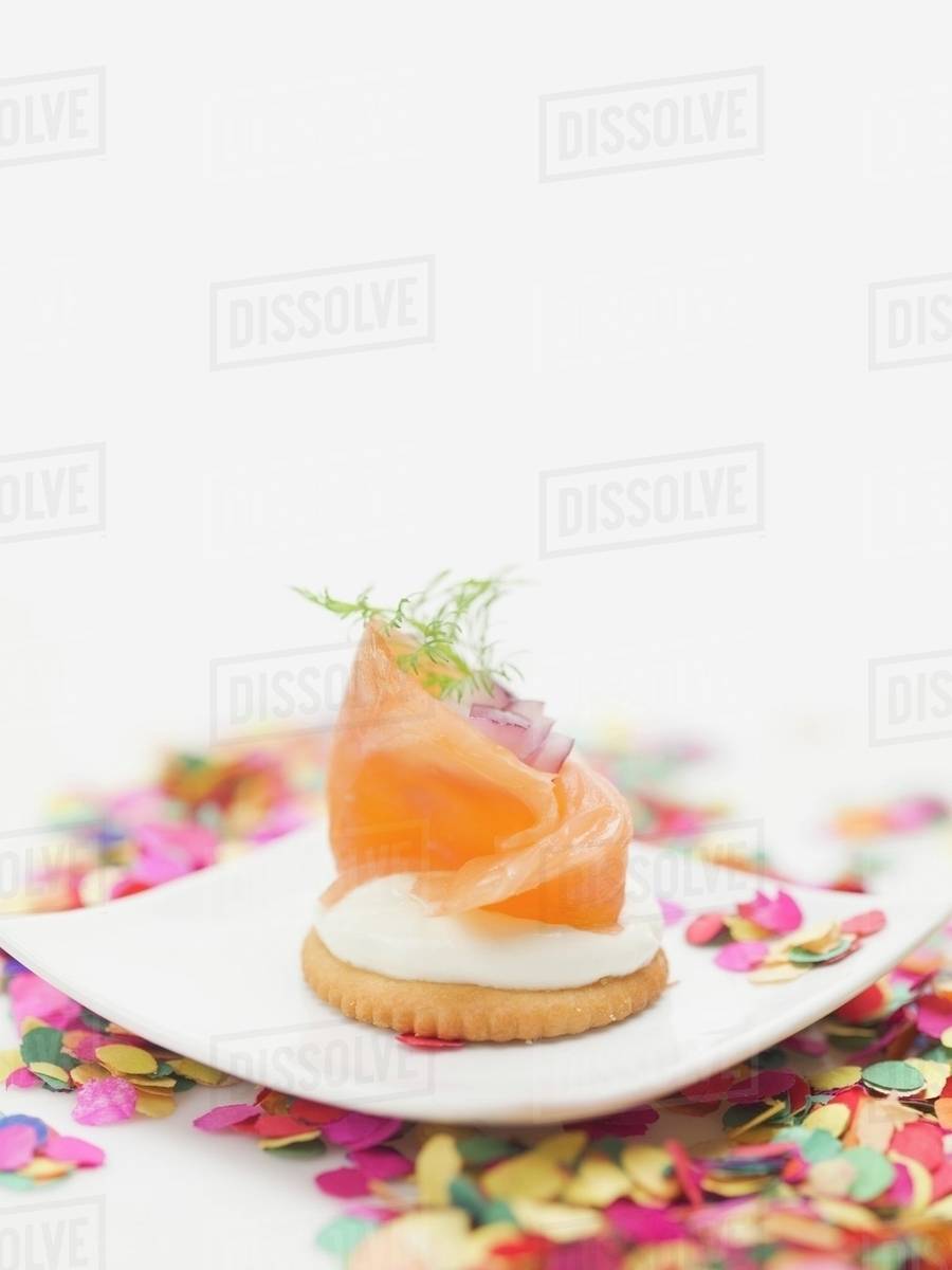 Smoked salmon on cracker on plate surrounded by confetti - Royalty-free ...