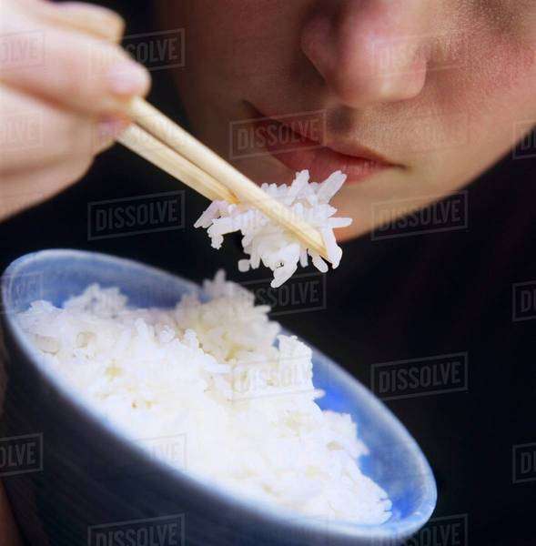 A Person Eating Rice with Chopsticks - Stock Photo - Dissolve