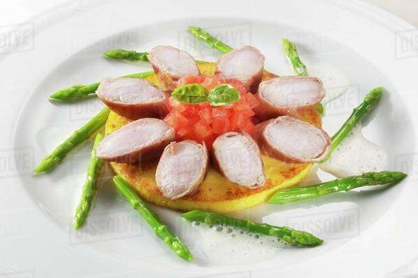 Rabbit loin & diced tomato on pancake, surrounded by asparagus - Stock ...