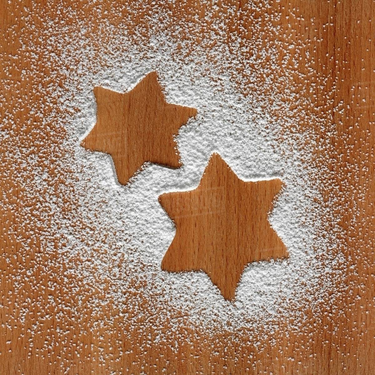 Star shapes in icing sugar on wooden background - Stock Photo - Dissolve