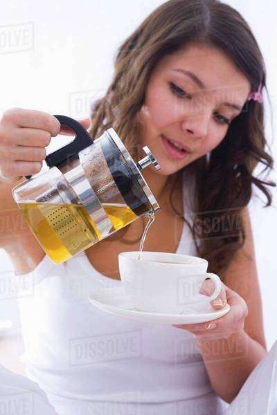 Girl pouring tea into a cup - Royalty-free Stock Photo | Dissolve