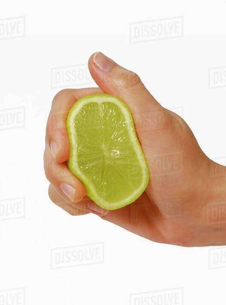 Hand lightly squeezing half a lime - Stock Photo - Dissolve