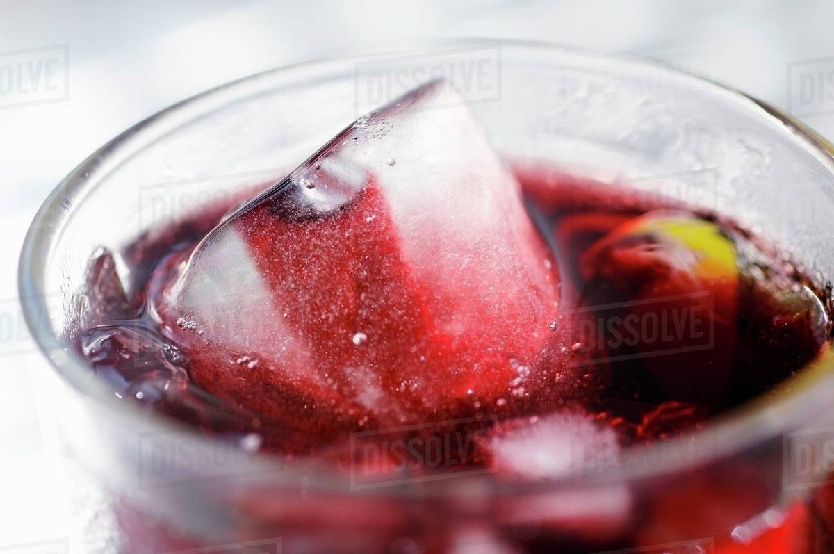 Red fruit juice with ice cubes in a glass - Stock Photo - Dissolve