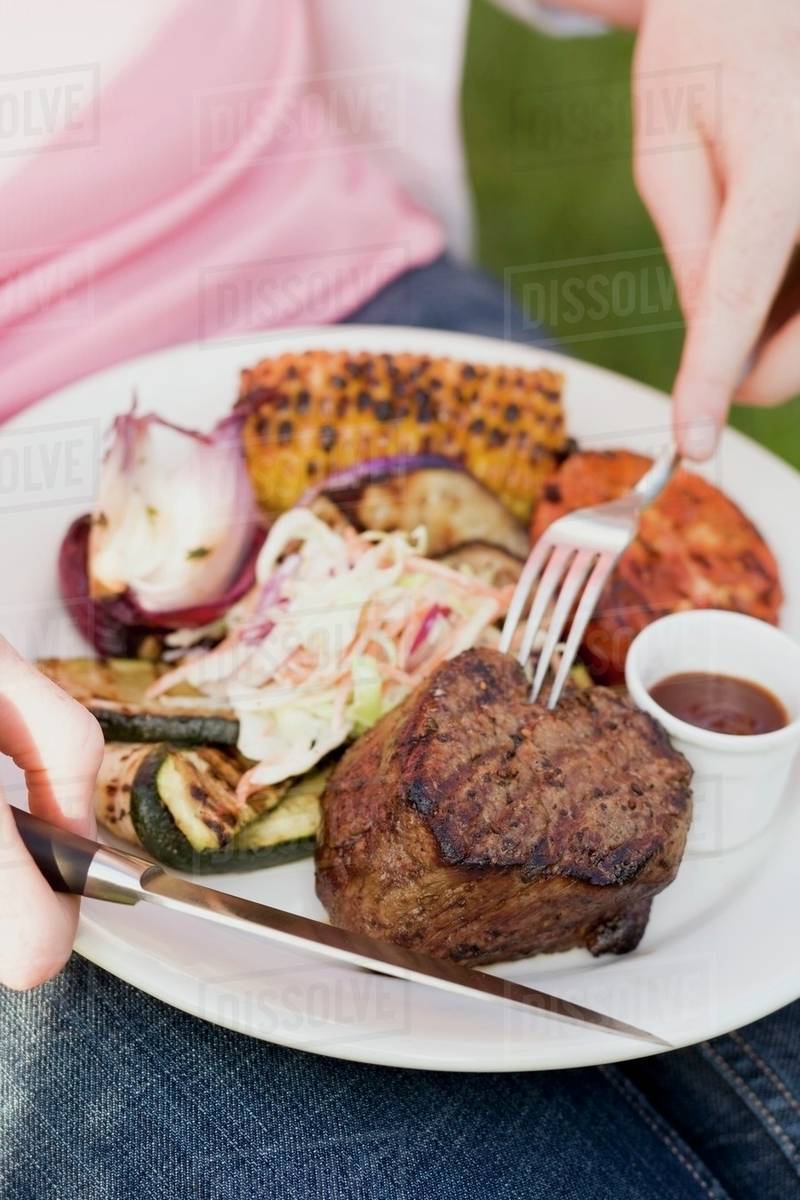 Seated woman eating grilled beef steak - Royalty-free Stock Photo ...
