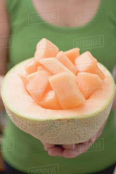 Woman holding diced melon in hollowed-out cantaloupe melon - Royalty ...