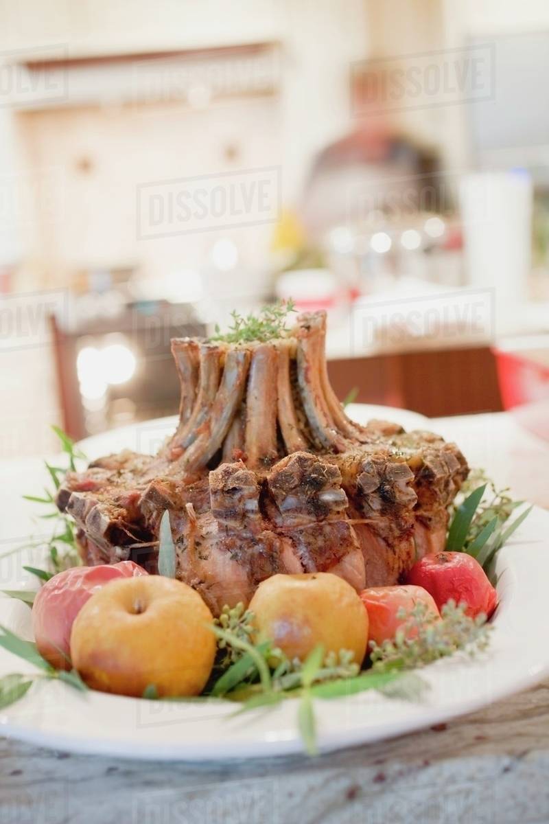 Roast rack of pork with apples, woman in background - Stock Photo ...
