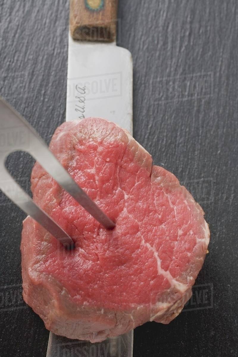 Pricking beef fillet with carving fork - Stock Photo - Dissolve