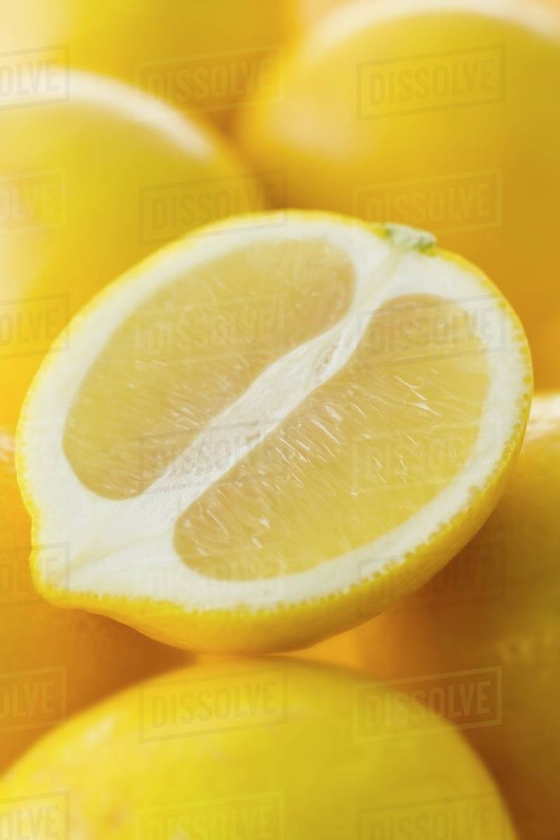 Half a lemon on several whole lemons - Stock Photo - Dissolve