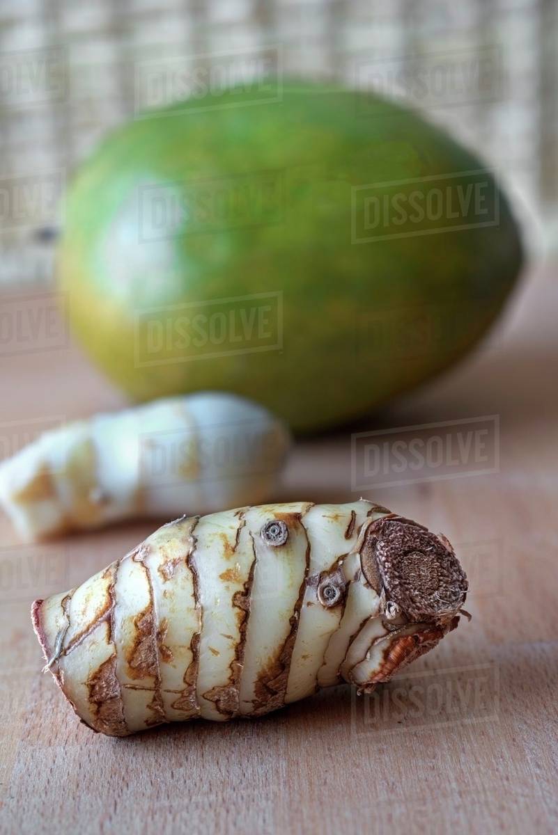 Fresh galgant with a mango in the background - Stock Photo - Dissolve