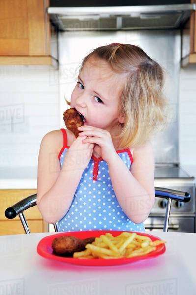 A little girl eating a chicken leg with chips - Royalty-free Stock ...