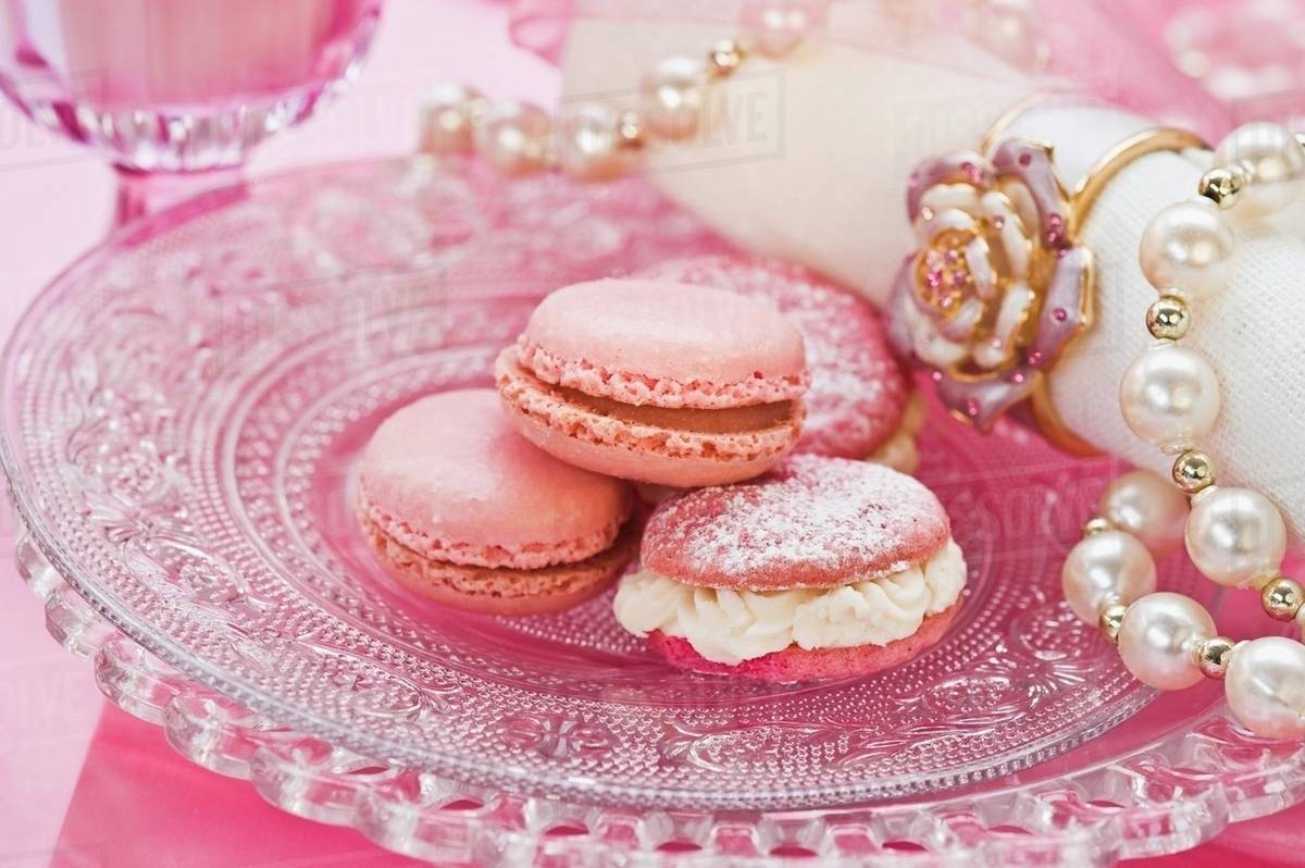 Pink macaroons on a glass plate with a pearl necklace and a napkin ...