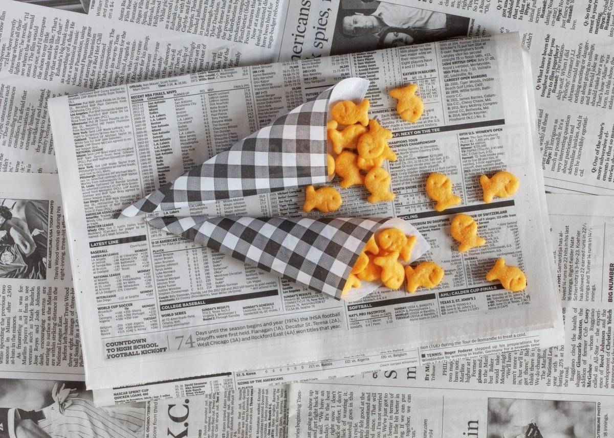 Fish shaped crackers in paper cones on a piece of newspaper - Royalty ...