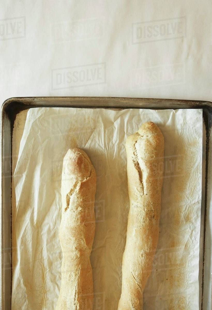 Two baguette on a baking tray lined with baking paper (seen from above ...