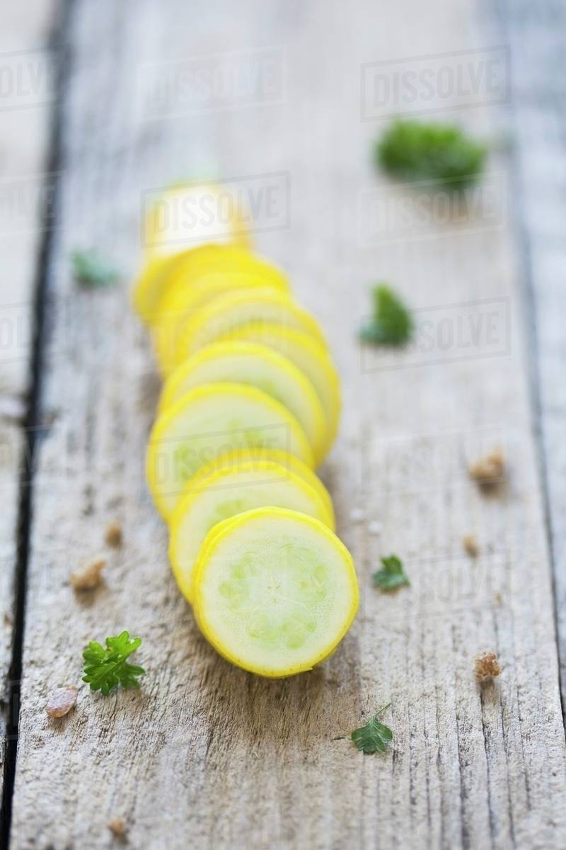 Courgette slices on a wooden surface. - Royalty-free Stock Photo | Dissolve