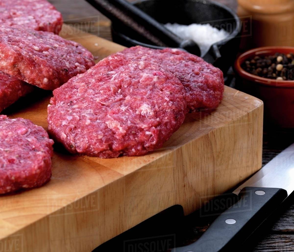 Raw wild boar burger on a chopping board - Stock Photo - Dissolve