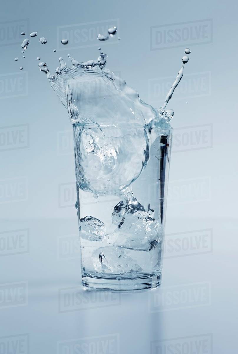 Ice Cubes Splashing into a Glass of Water with a Lemon Wedge - Royalty ...