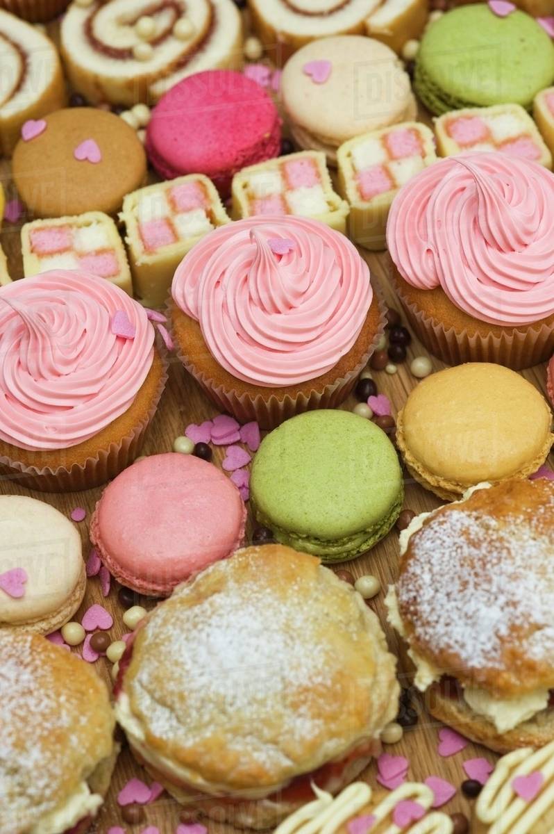 Rows of cupcakes, scones, macarons, Swiss rolls and pieces of mini ...