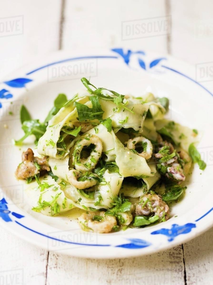 Ribbon pasta with herbs and calamari - Stock Photo - Dissolve